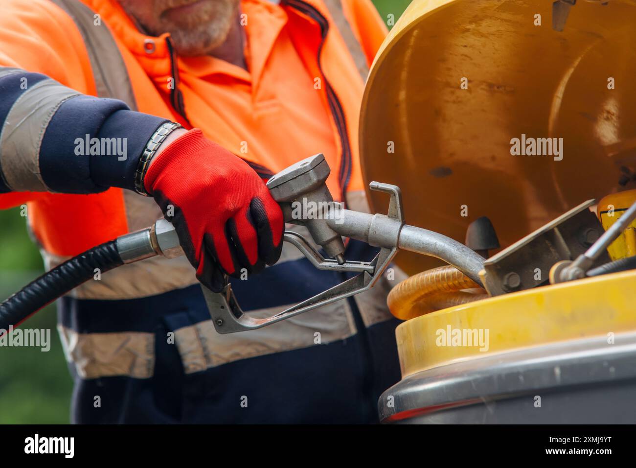 Builder in safety gloves filling excavator with diesel fuel on building ...
