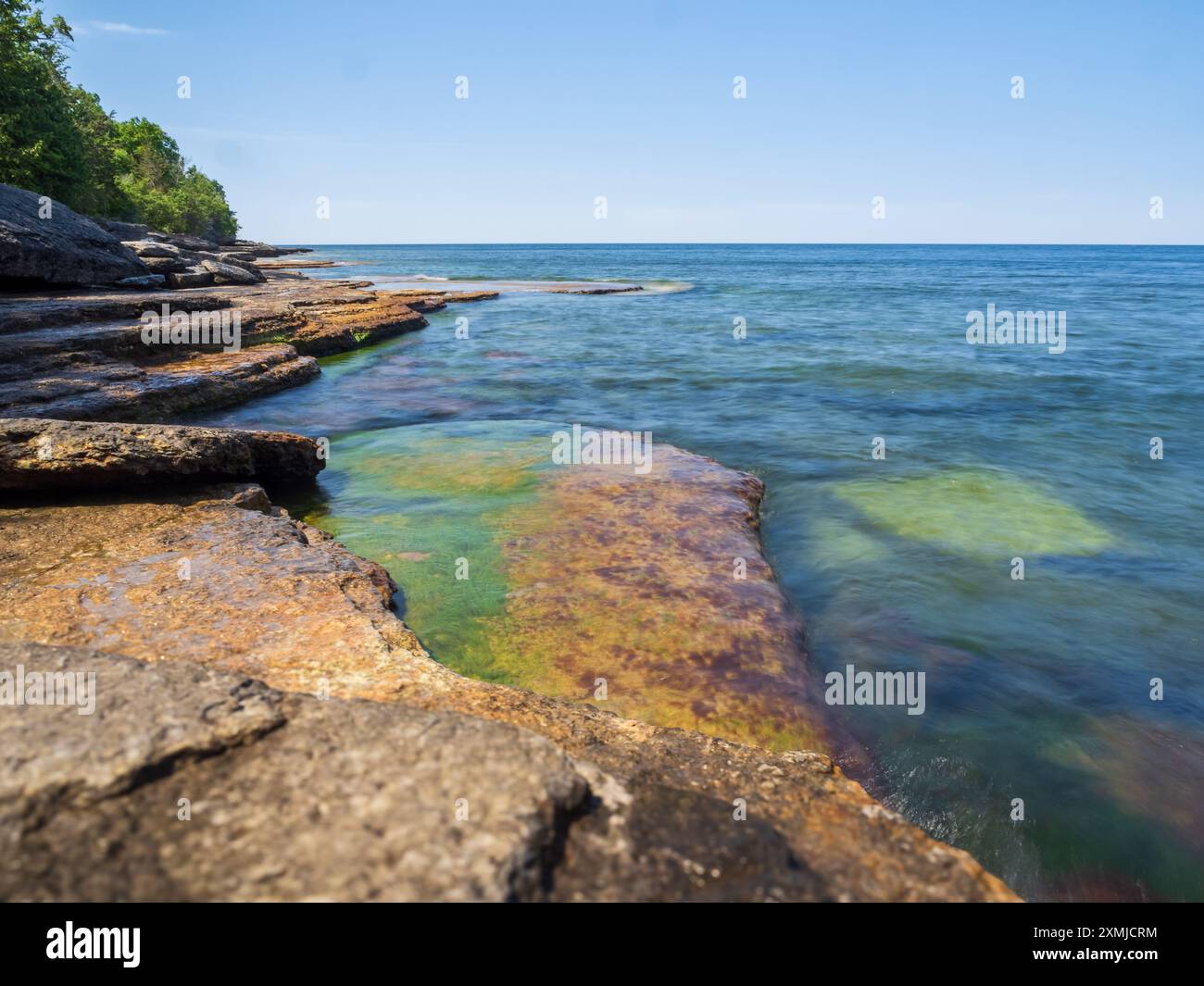 Sunlight dances on the clear water cascading over moss-covered cliffs ...