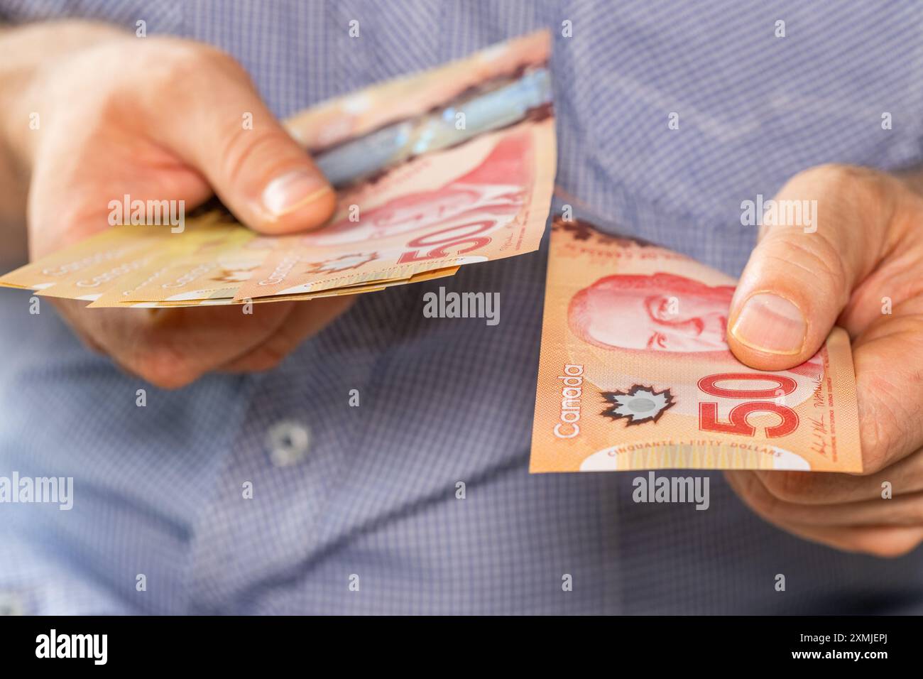 Canada money, Man holding a bundle of Canadian dollars in his hand and ...