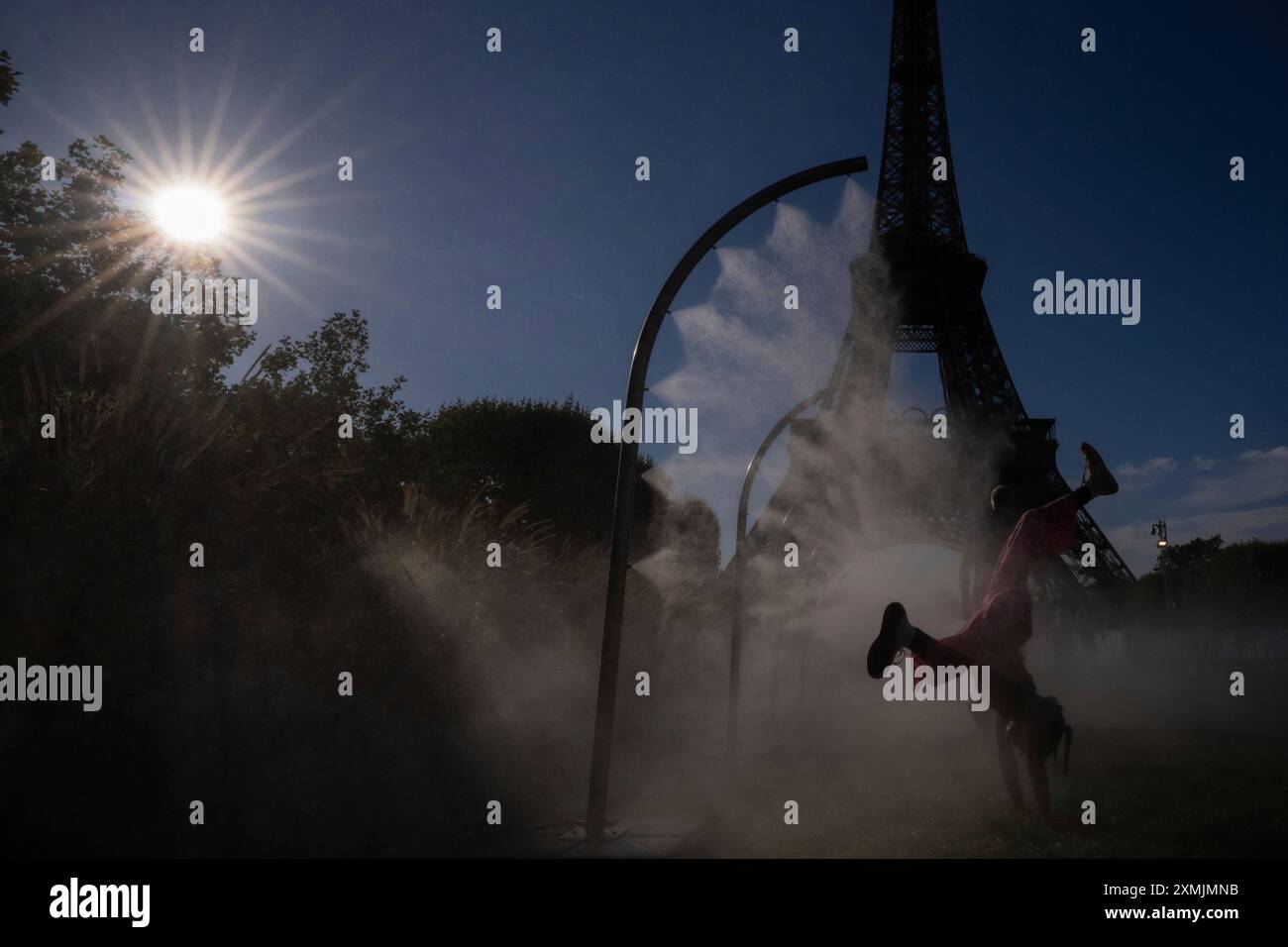 People cool off under a mist outside the Eiffel Tower Stadium at the ...