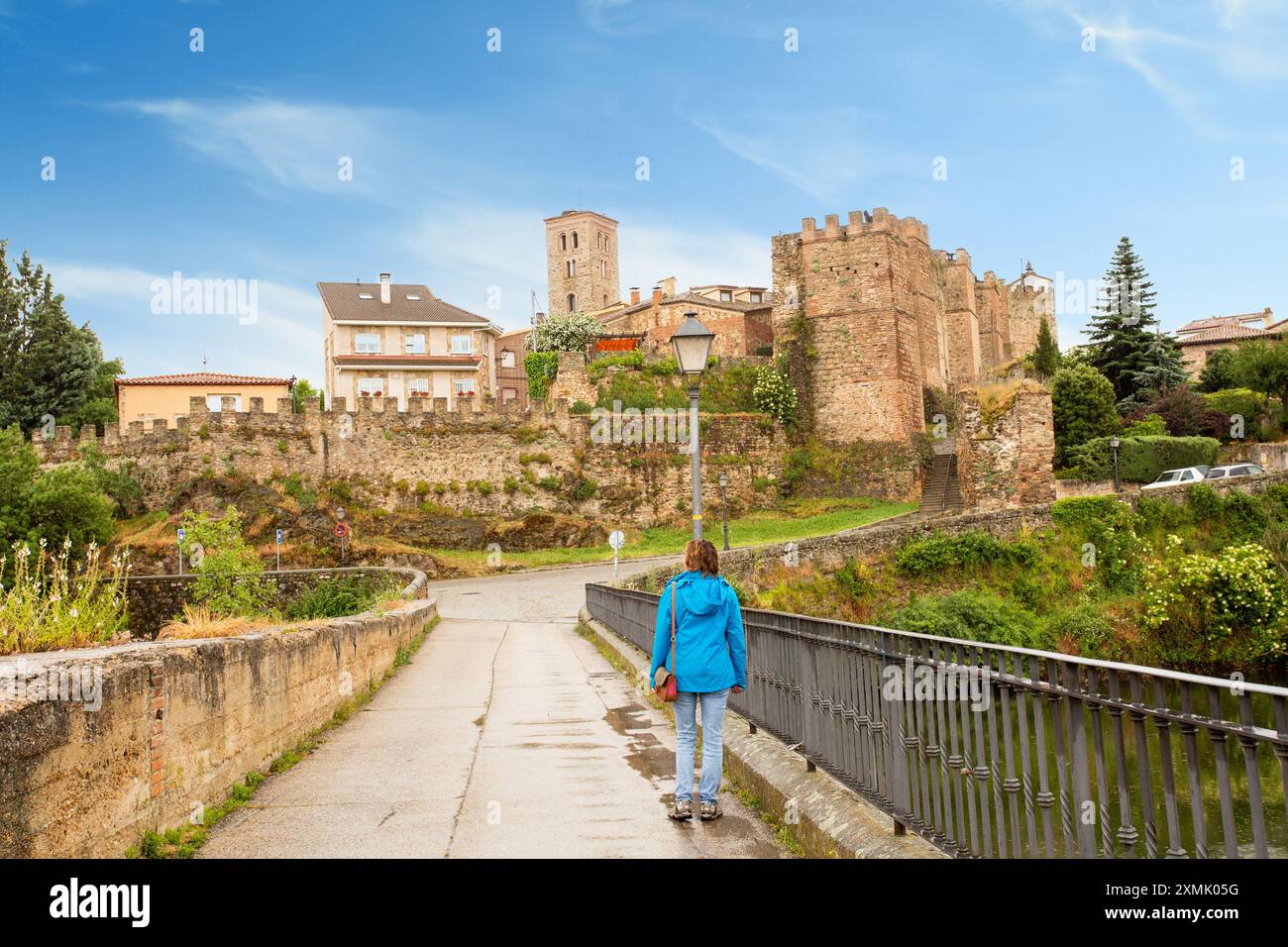 Woman walking towards the Spanish medieval walled city of El Burgo de ...