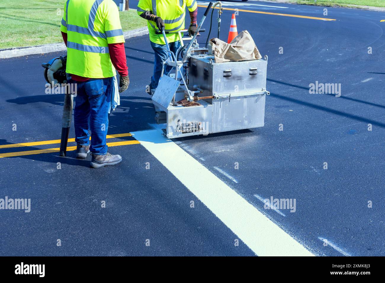 Using an airbrush machine, workers apply marking signs after asphalt ...