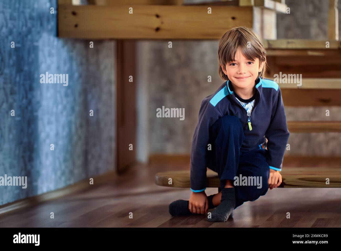Smiling slim European male child dressed in sports uniform sits on step ...
