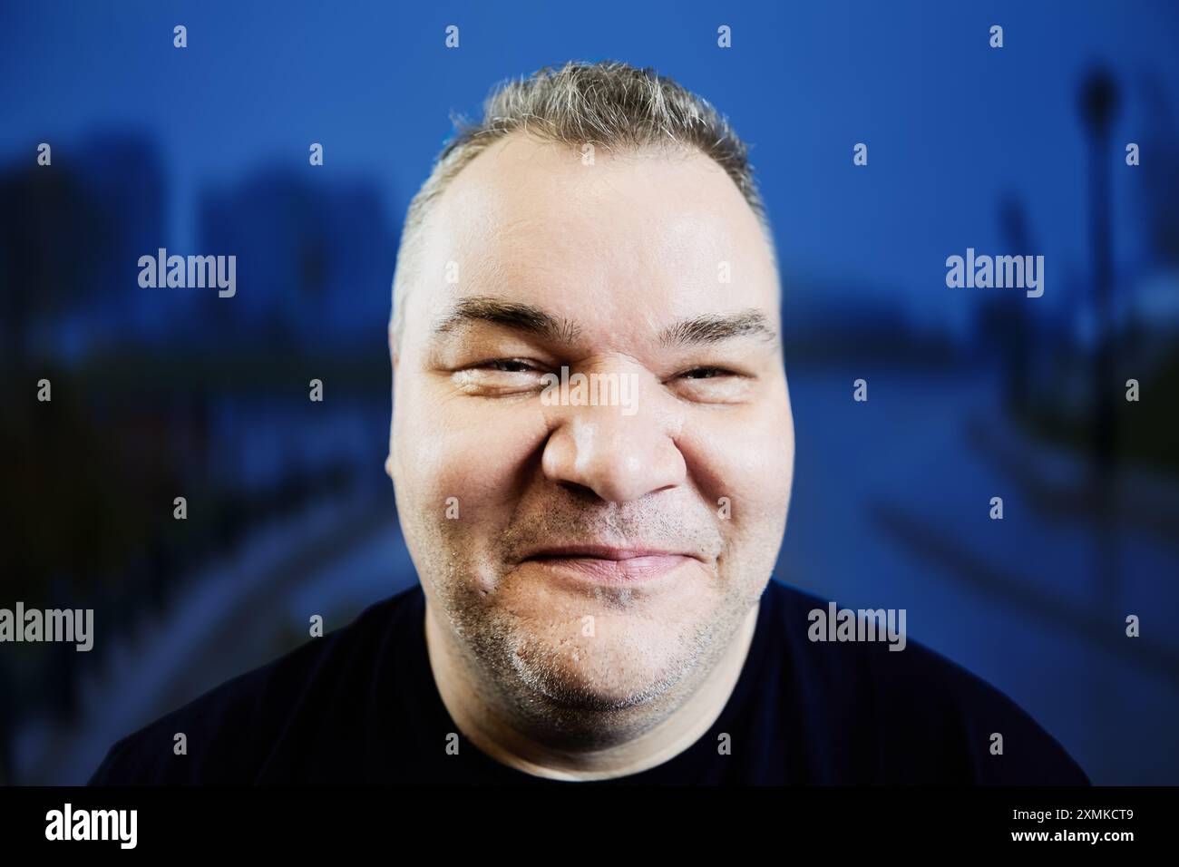 Mysterious smile of fat white man in her 40s, face close-up on blue ...