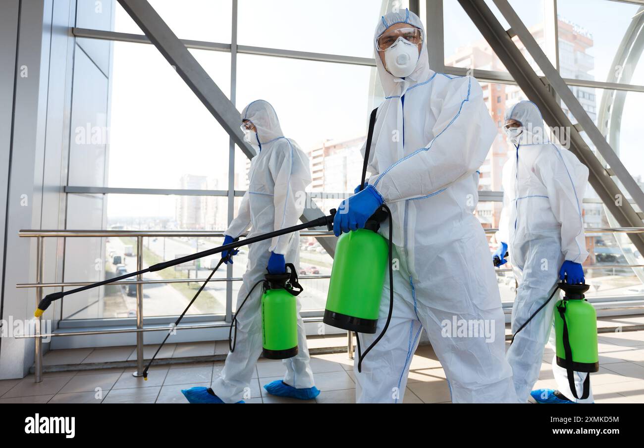 Professional workers in hazmat suits disinfecting indoor accommodation ...