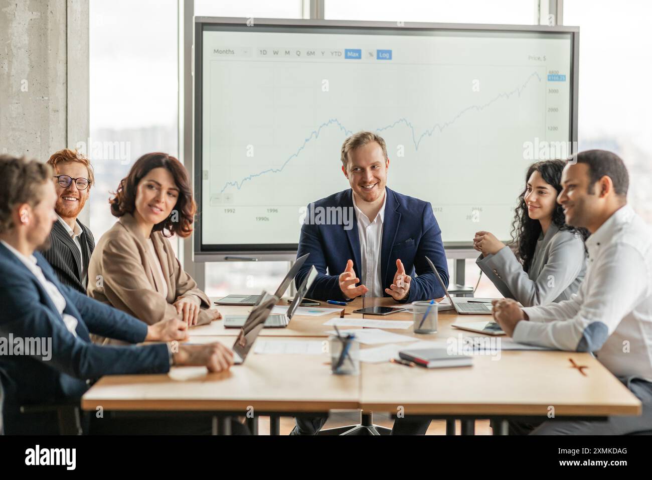 Business Team Meeting Around Table Discussing Graph on Screen Stock ...