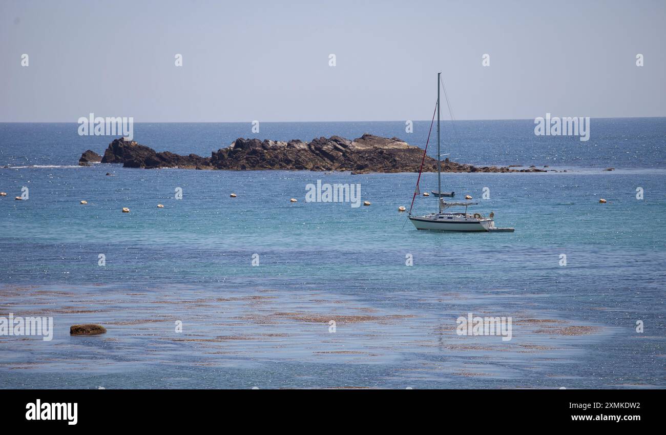 small Sailing boat without sails maneuvers between rocks protruding ...