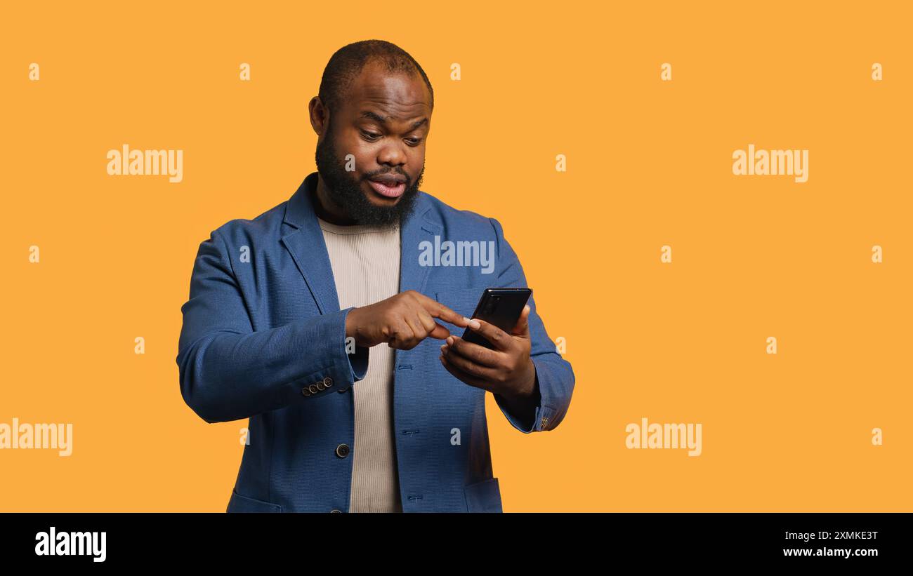 Portrait of joyous man holding cellphone celebrating, throwing fists in ...
