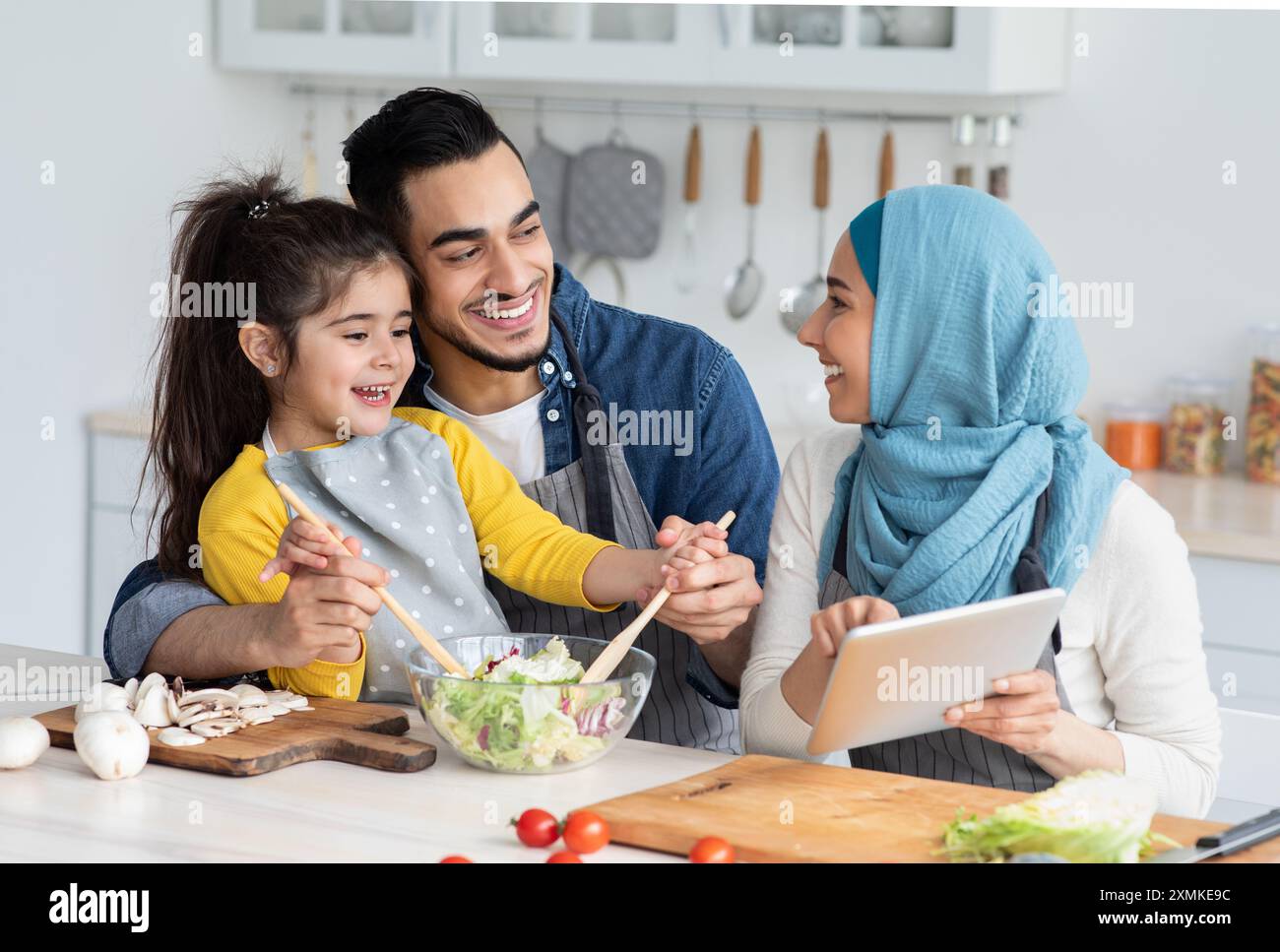 Happy Islamic Family Checking Recipe On Digital Tablet While Cooking In ...