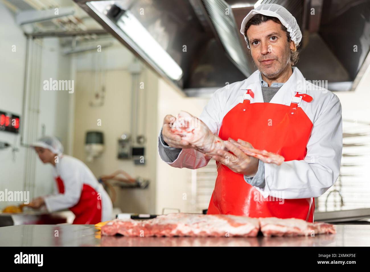 Butcher standing at cutting table with raw lamb leg Stock Photo - Alamy