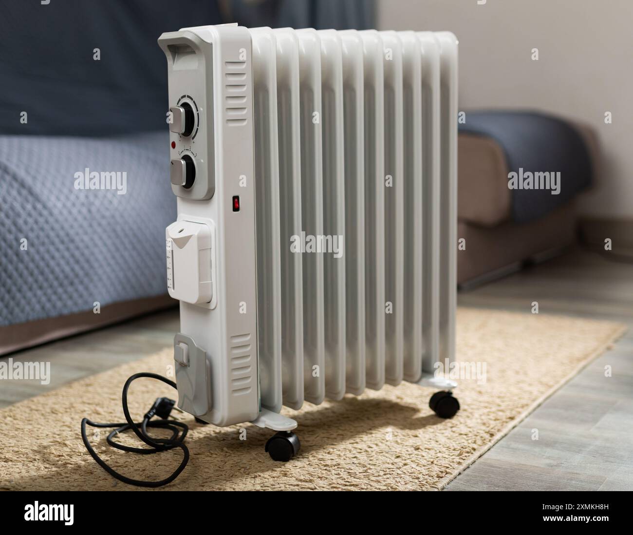 White metal portable oil heater standing in home room Stock Photo - Alamy