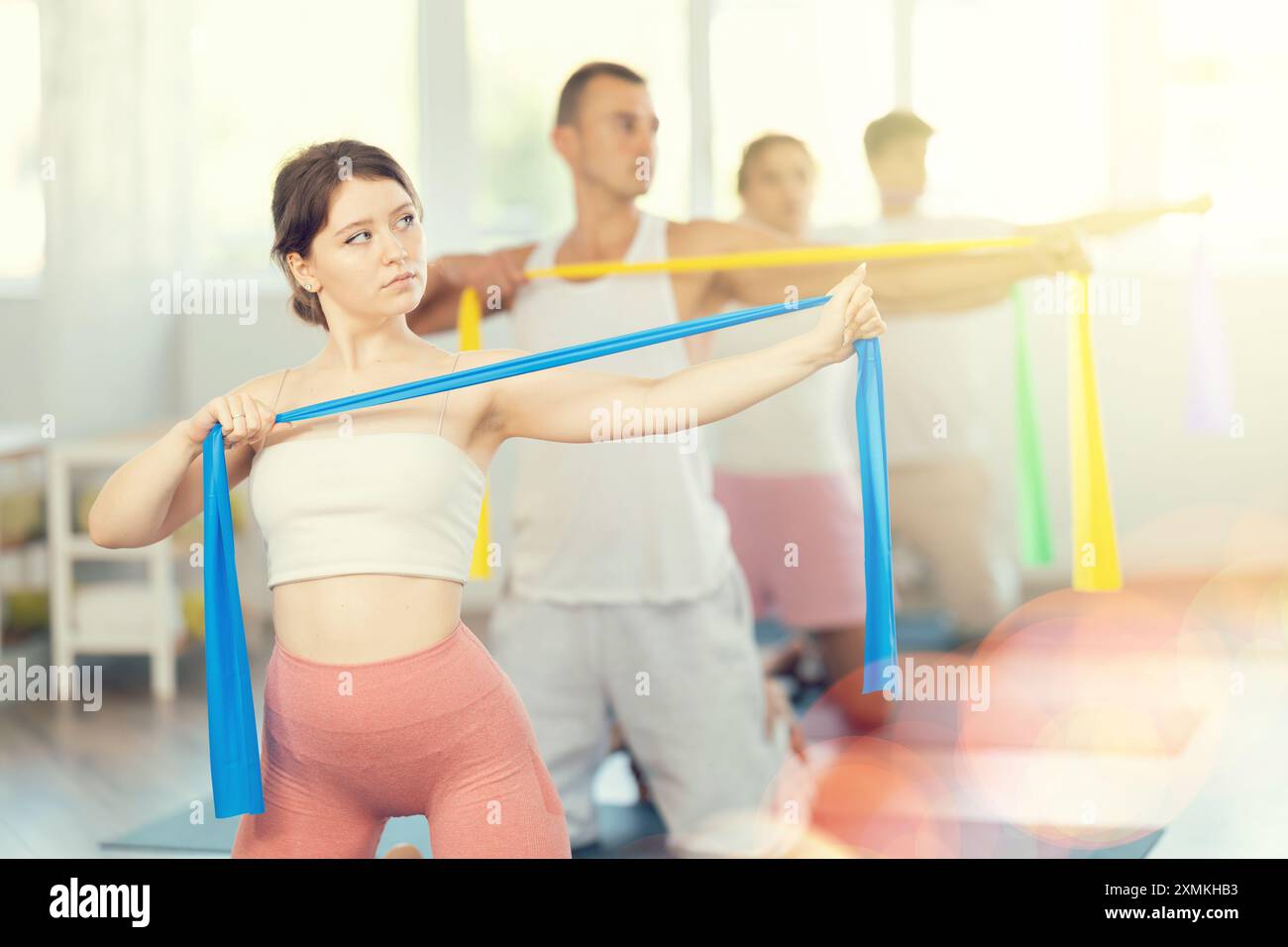 Young girl doing arm workout with resistance band standing on knees ...