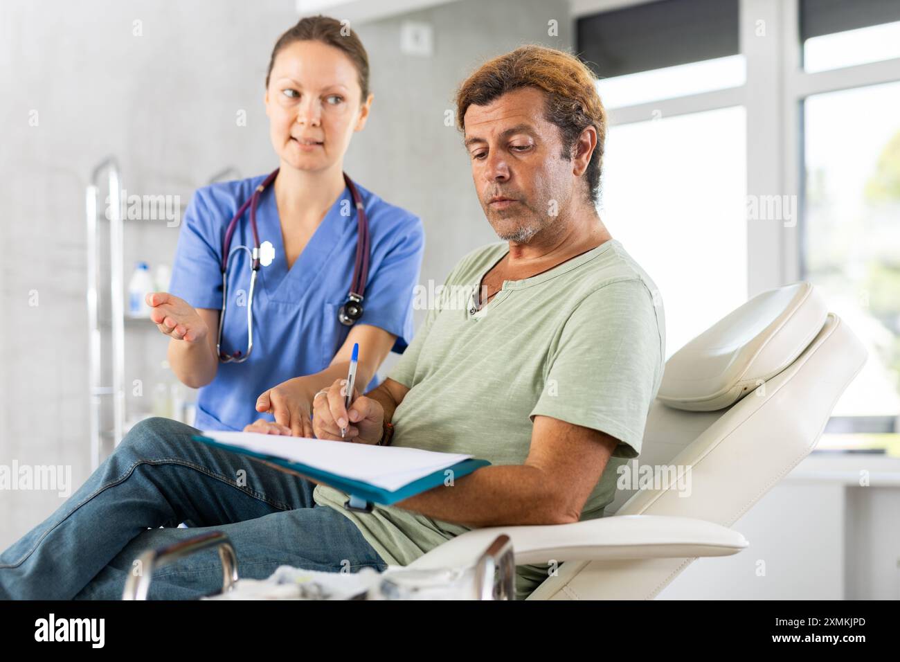 Patient signing informed consent form during medical consultation with ...
