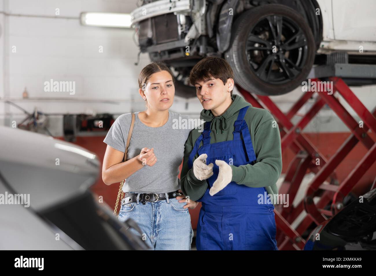 Interested female client talking to young auto mechanic Stock Photo - Alamy