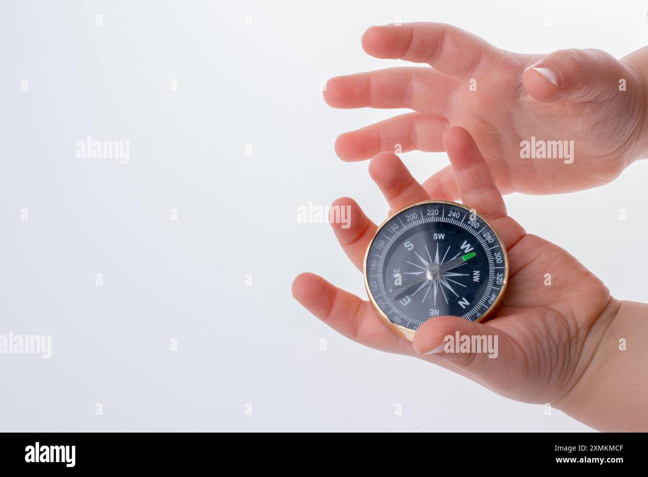 Child hand holding a compass on a white background Stock Photo - Alamy