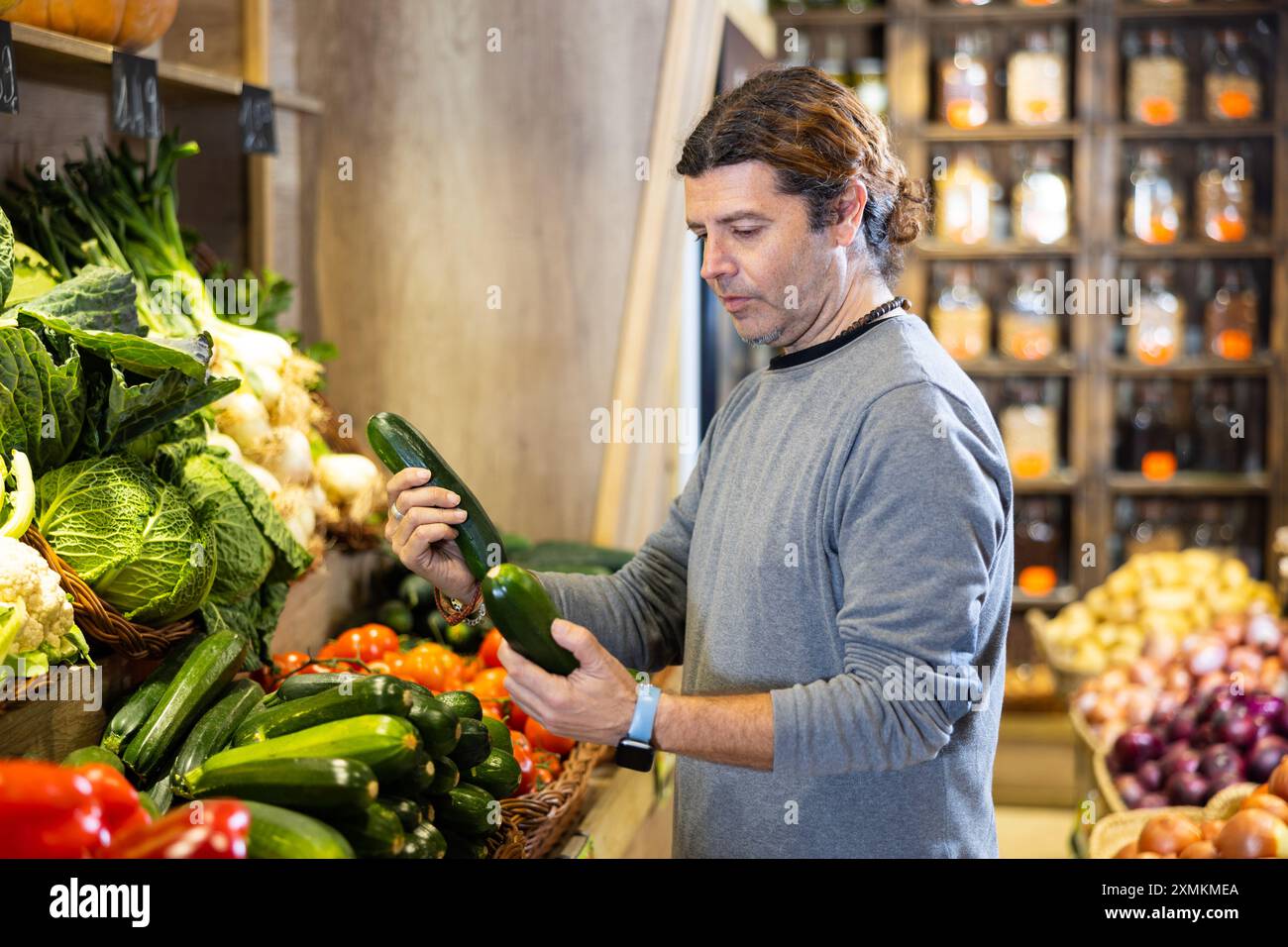 Man looking fresh cucumber in grocery store Stock Photo - Alamy