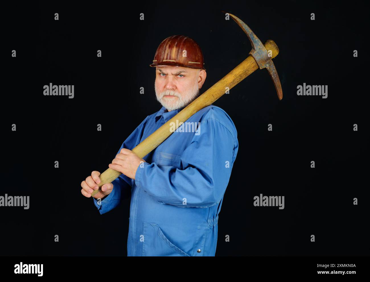 Serious builder man in uniform with pick-axe on shoulder. Mining ...