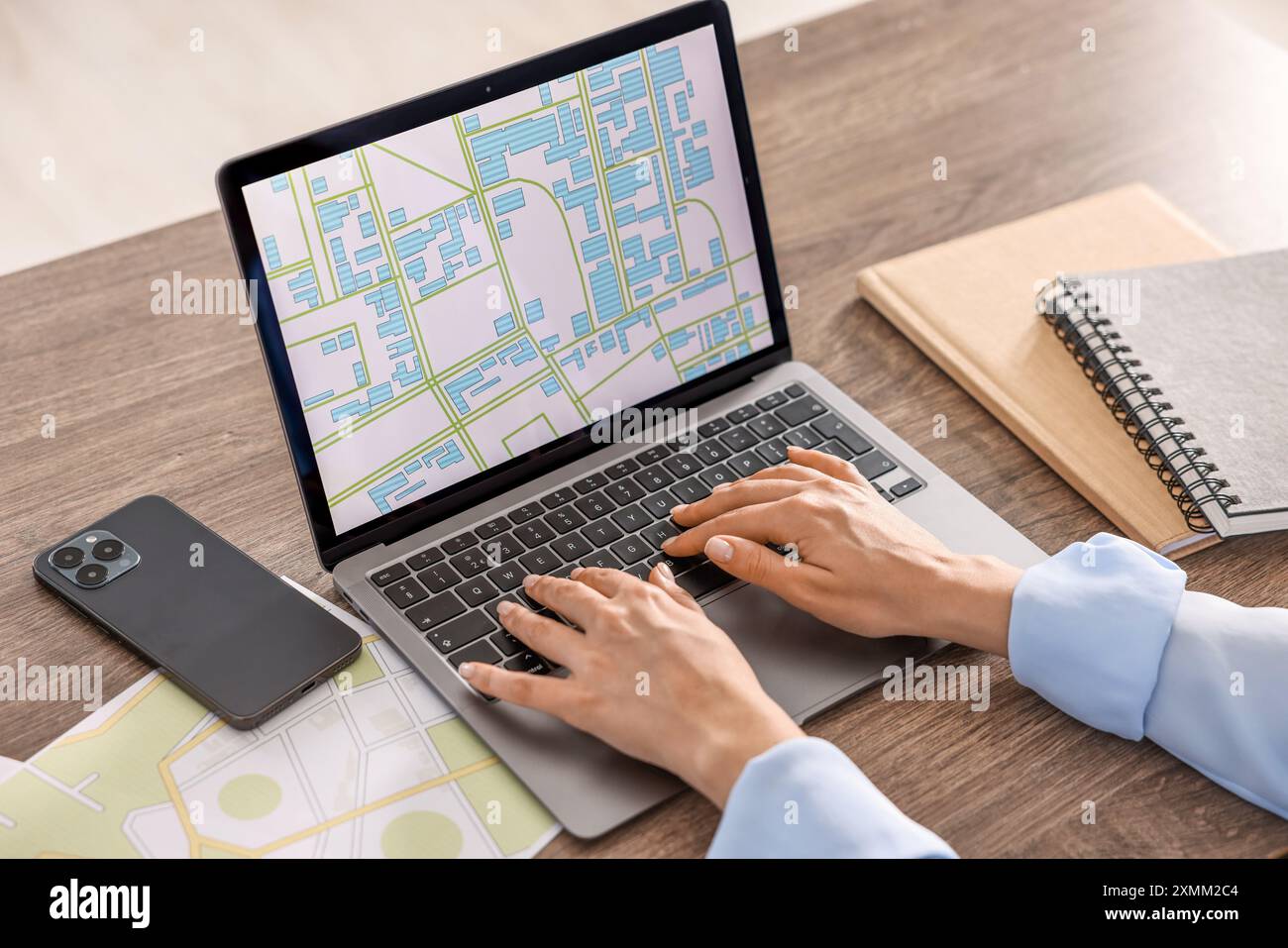 Cartographer working with cadastral map on laptop at wooden table in ...