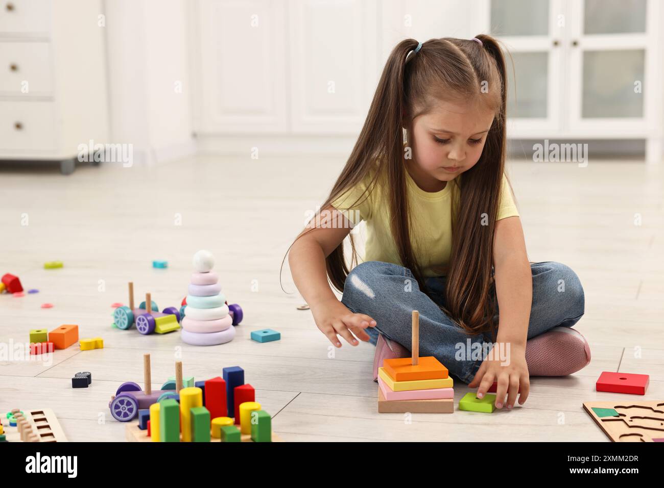 Cute little girl playing with toy pyramid on floor indoors Stock Photo ...