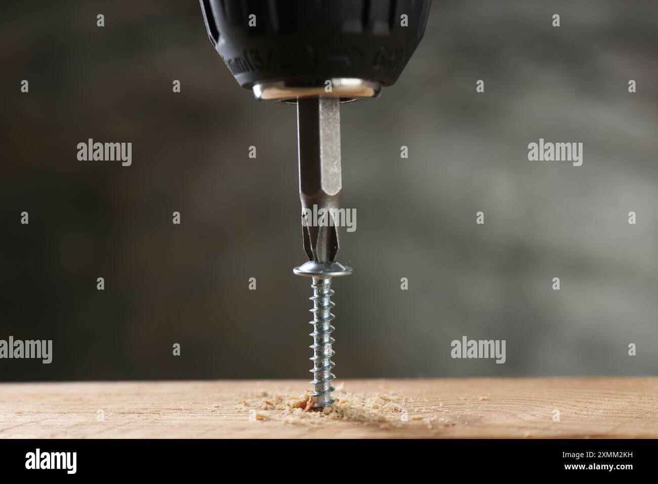 Screwing screw into wooden plank against gray background, closeup Stock ...