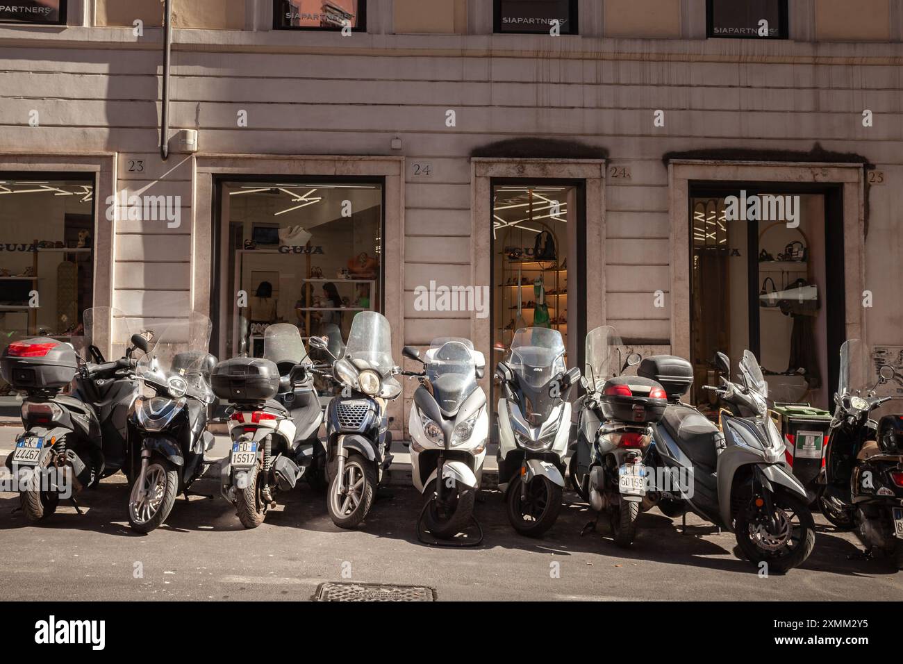 This photograph features a line of scooters parked along a street in ...
