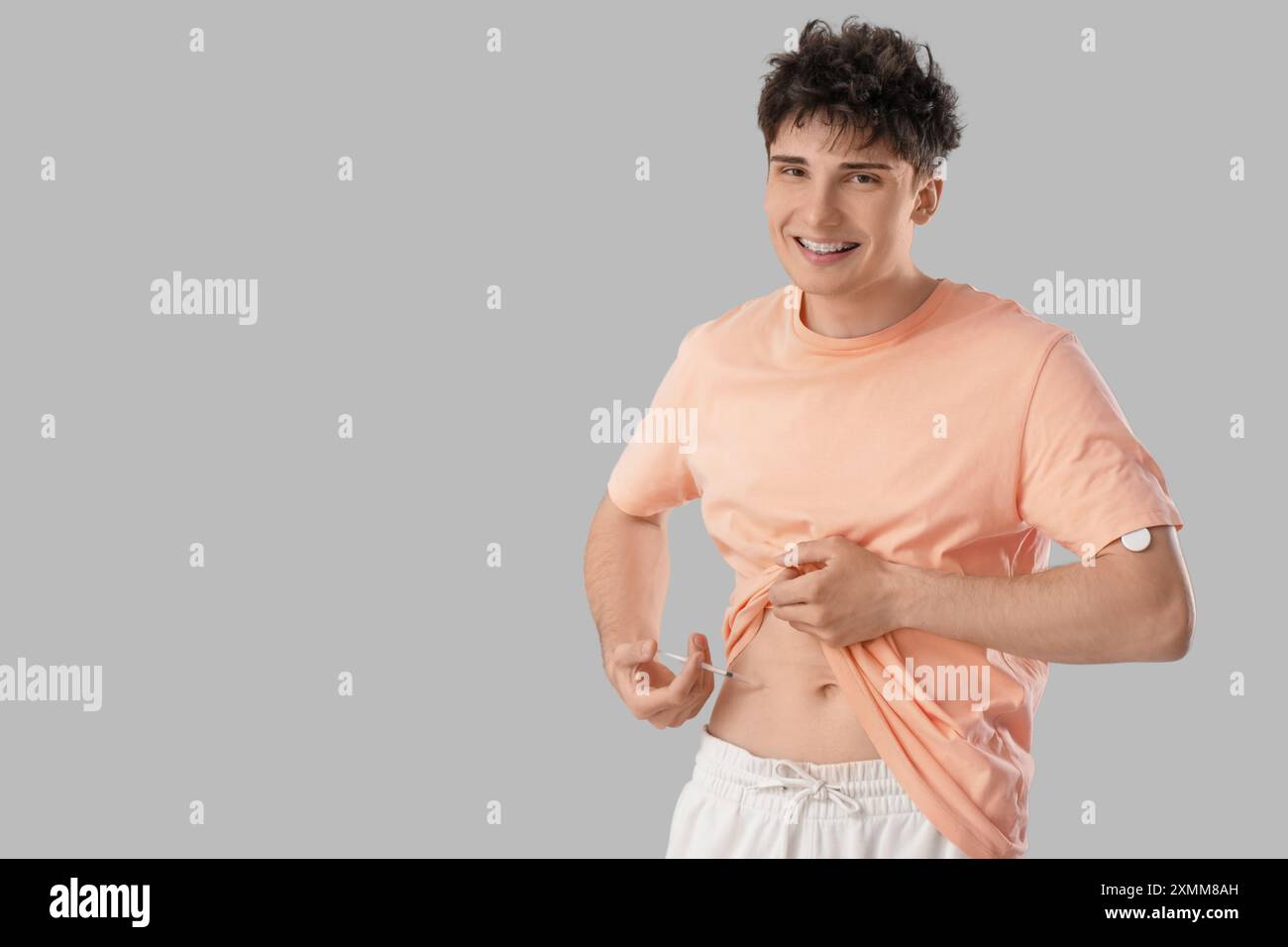 Diabetic young man with glucose sensor giving himself insulin injection ...