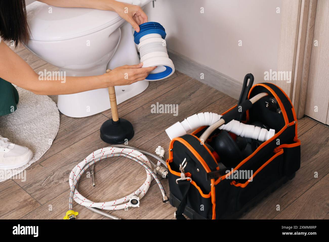 Female plumber fixing toilet bowl in restroom Stock Photo - Alamy