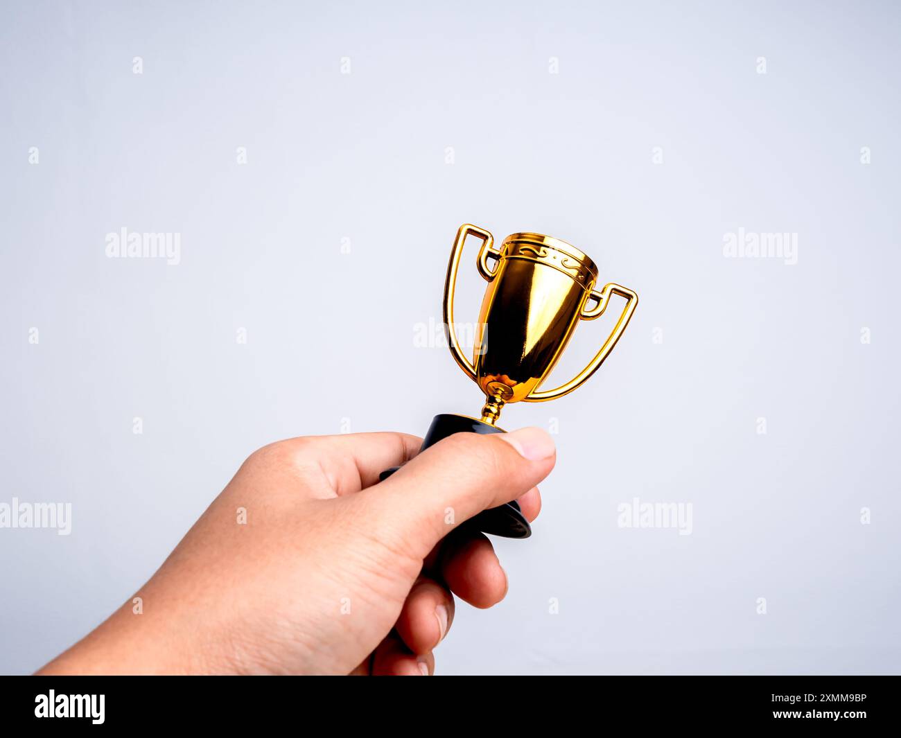 A gold trophy, brass steel, dual handle, in human hand, isolated on ...