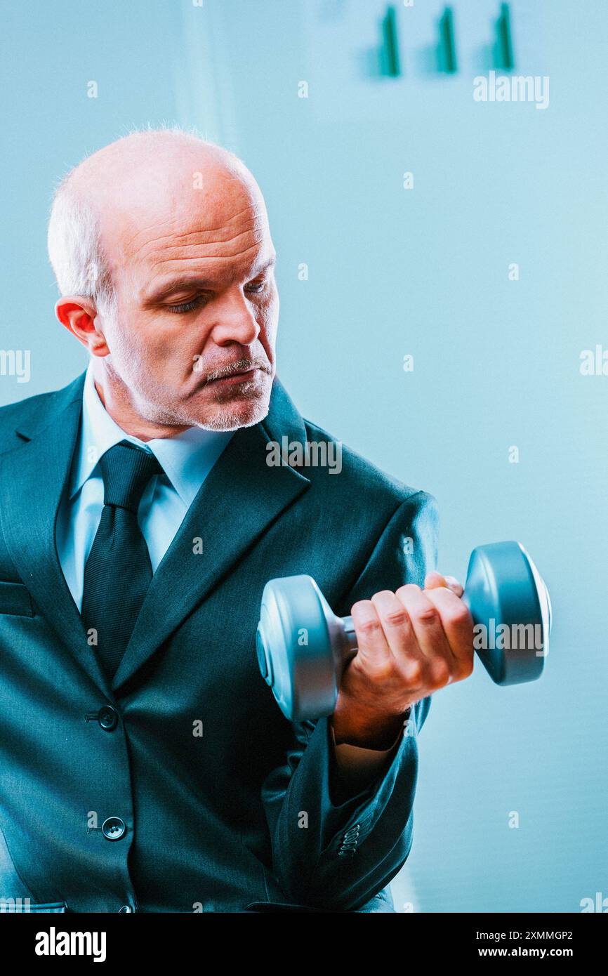 Determined businessman is lifting a dumbbell in his office, symbolizing ...