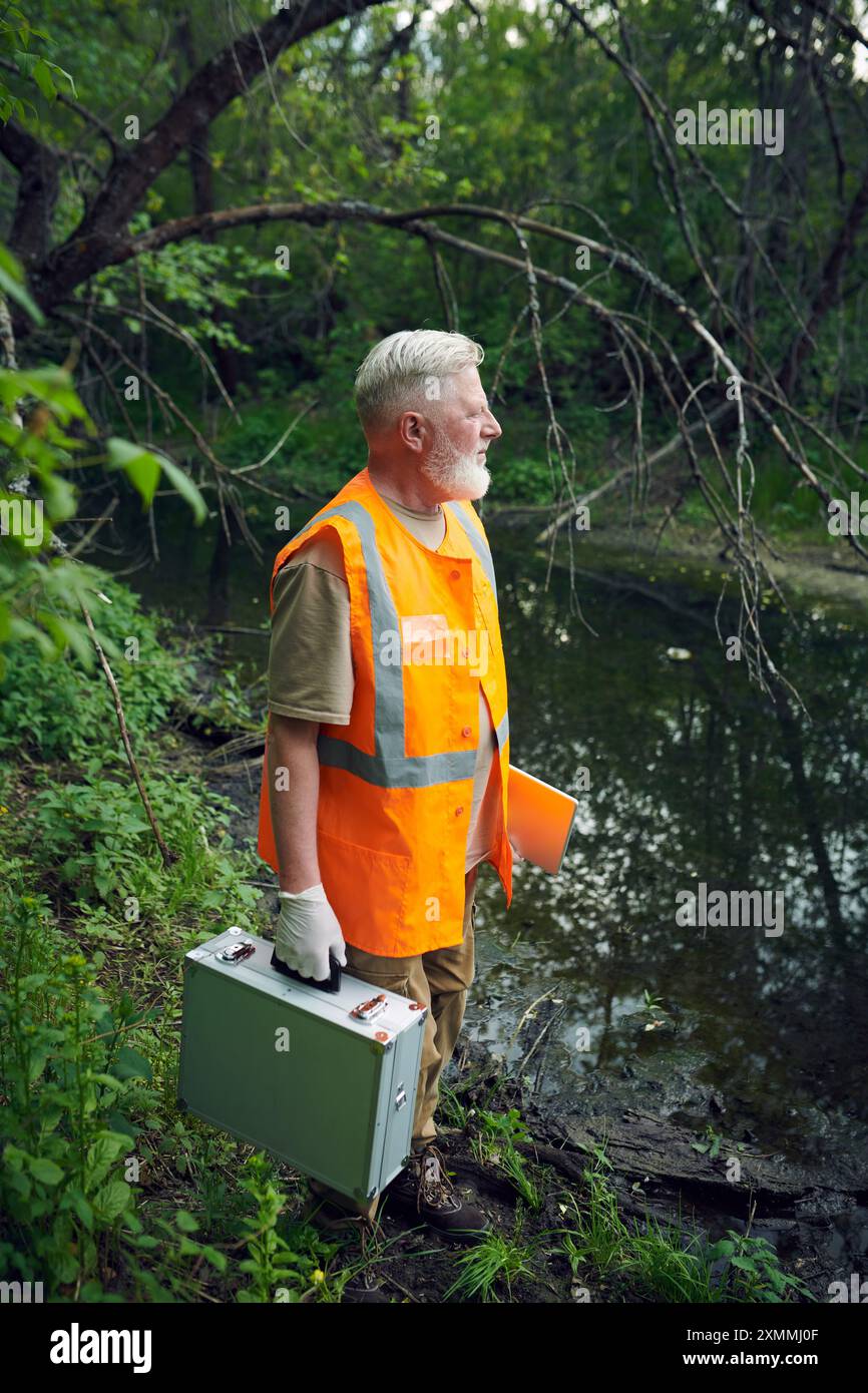 Vertical high angle view long shot of senior ecologist holding portable ...