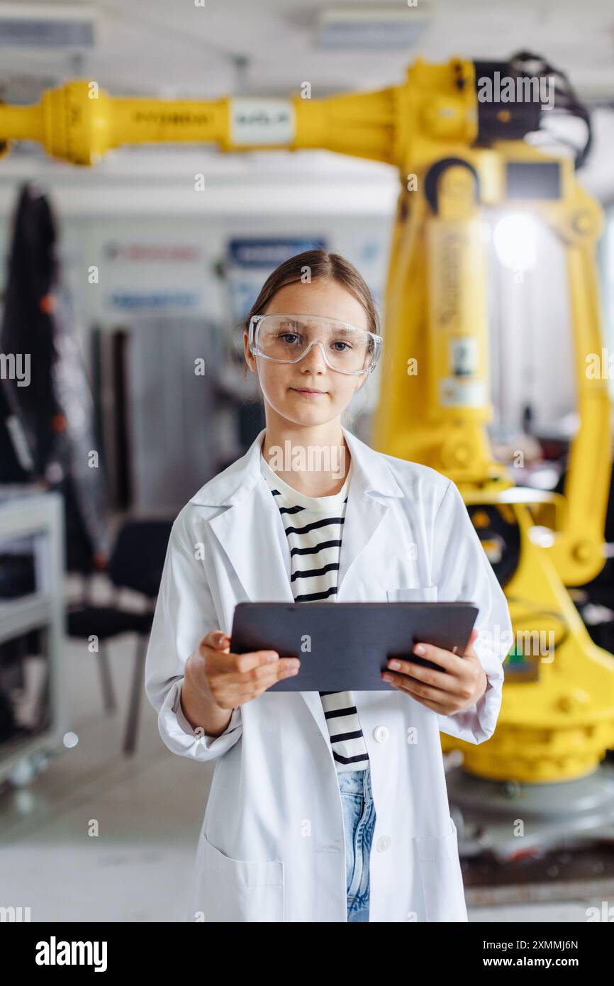 Portrait of young girl in robotic laboratory, wearing lab coat and ...