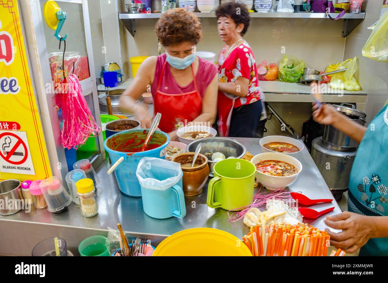 A lady prepares a food order at a stall in the food court in Tanjung ...