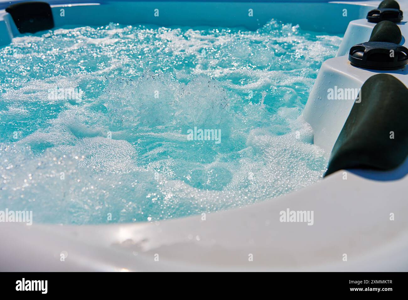 Close-up shot bubbling water in hot tub with headrests. Blue water in ...