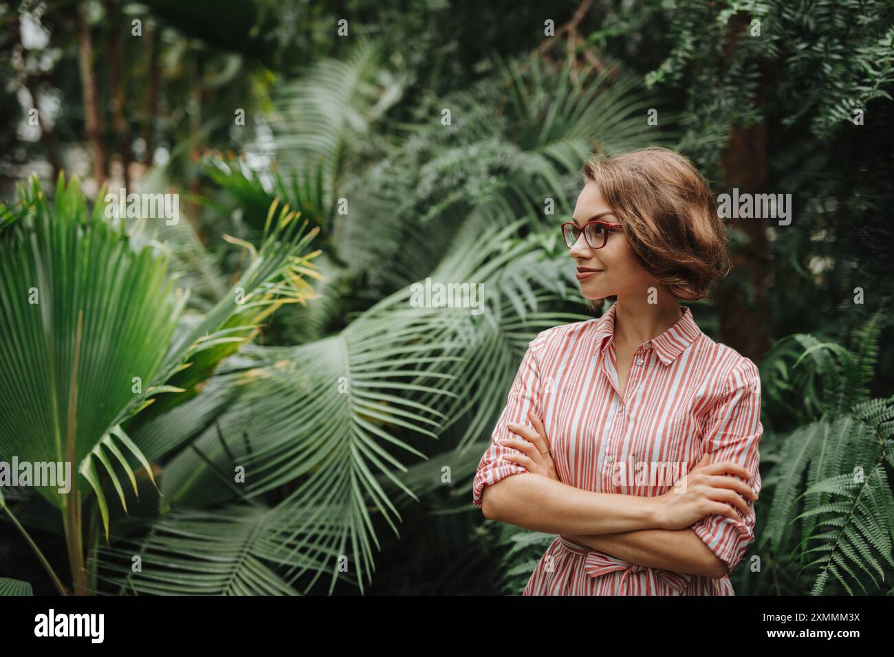 Beautiful woman standing in botanical garden, in the middle of lush ...
