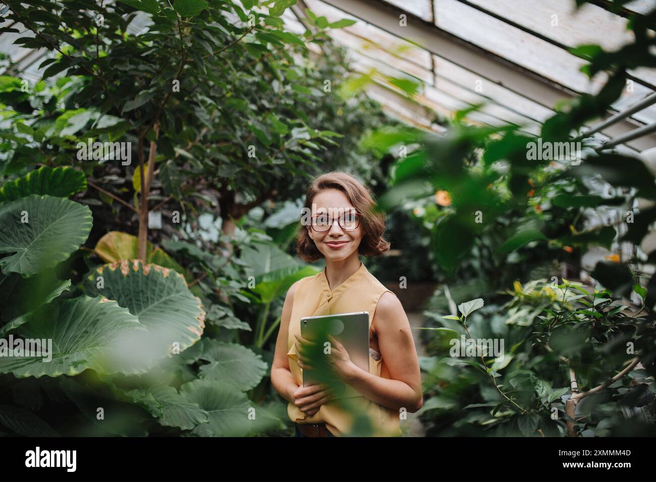 Beautiful woman standing in botanical garden, in the middle of lush ...
