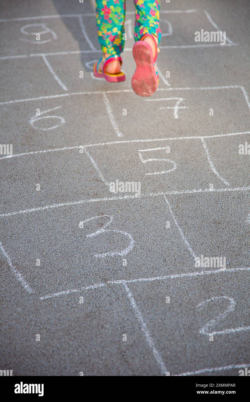 Hopscotch drawn with chalk on the pavement. Children's feet. Girl leg ...