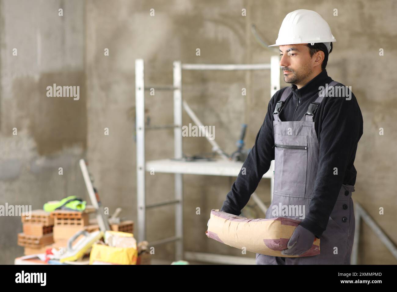 Construction worker lifting a concrete bag in a house under reformation ...