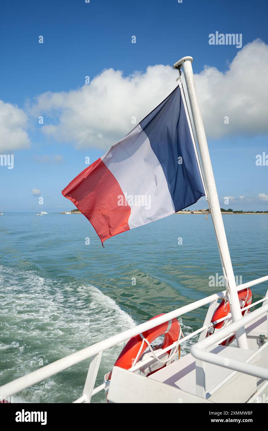 A french tricolor flag floating on the back from a ferry boat on ocean ...
