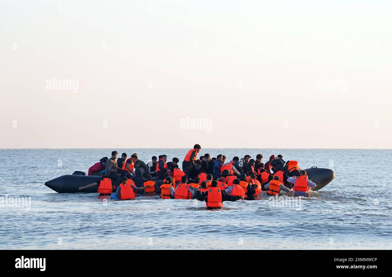 A group of people thought to be migrants wade through the sea to ...