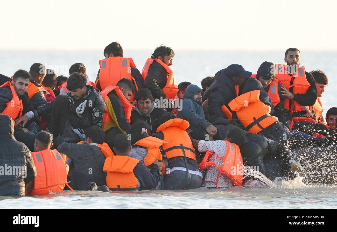 A group of people thought to be migrants wade through the sea to ...