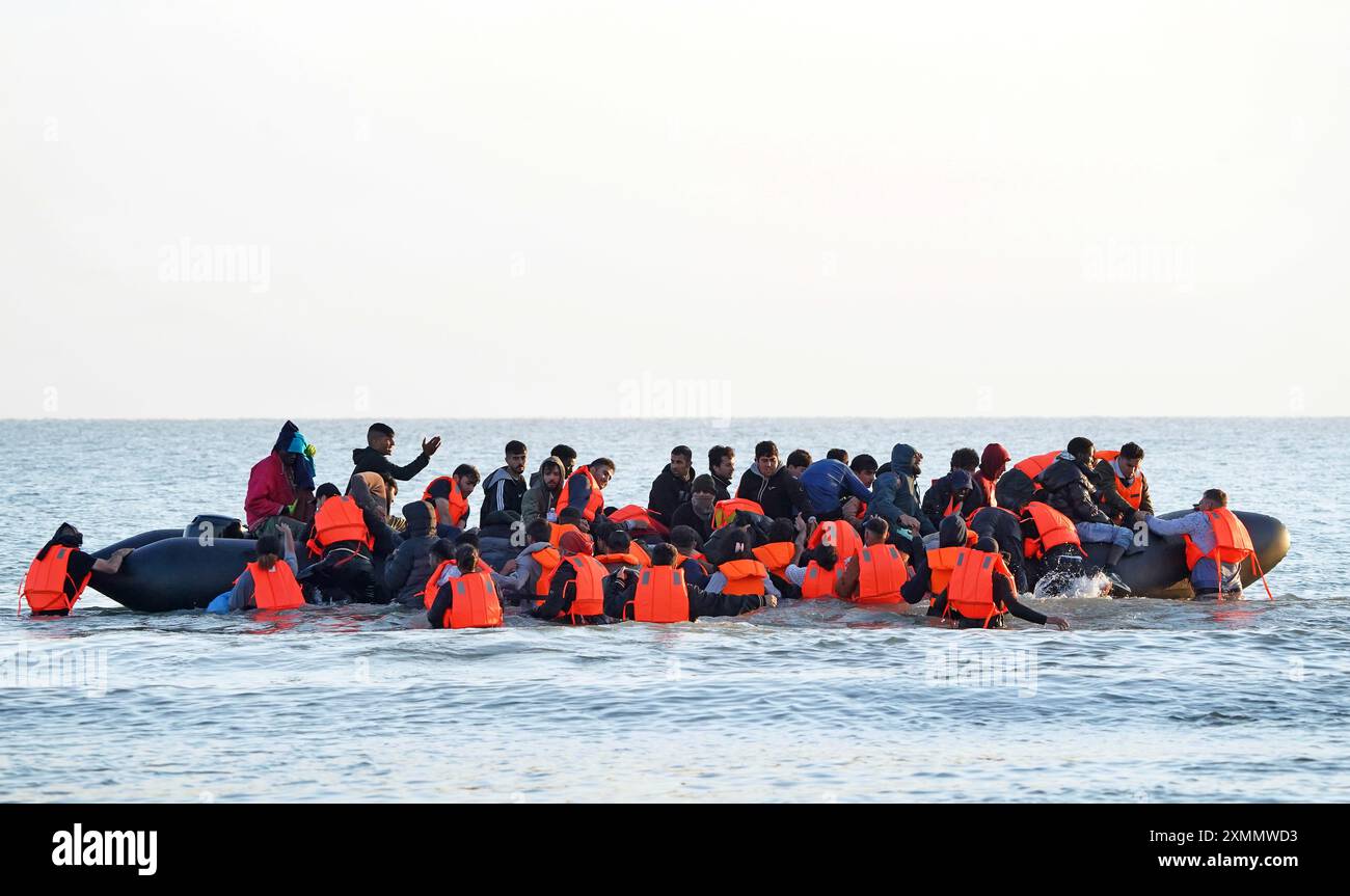 A group of people thought to be migrants wade through the sea to ...