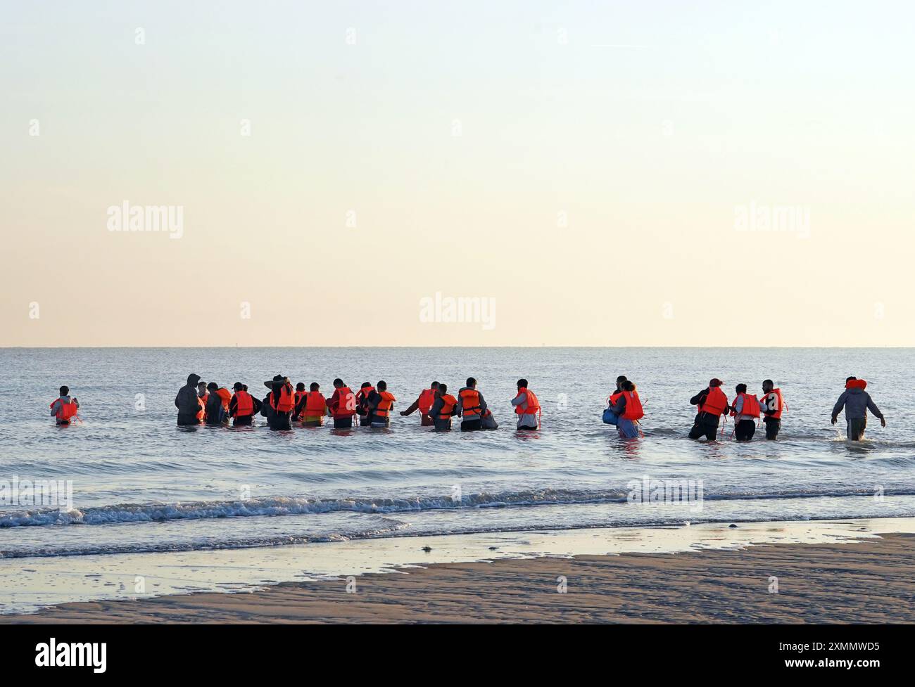 A group of people thought to be migrants wade through the sea in ...