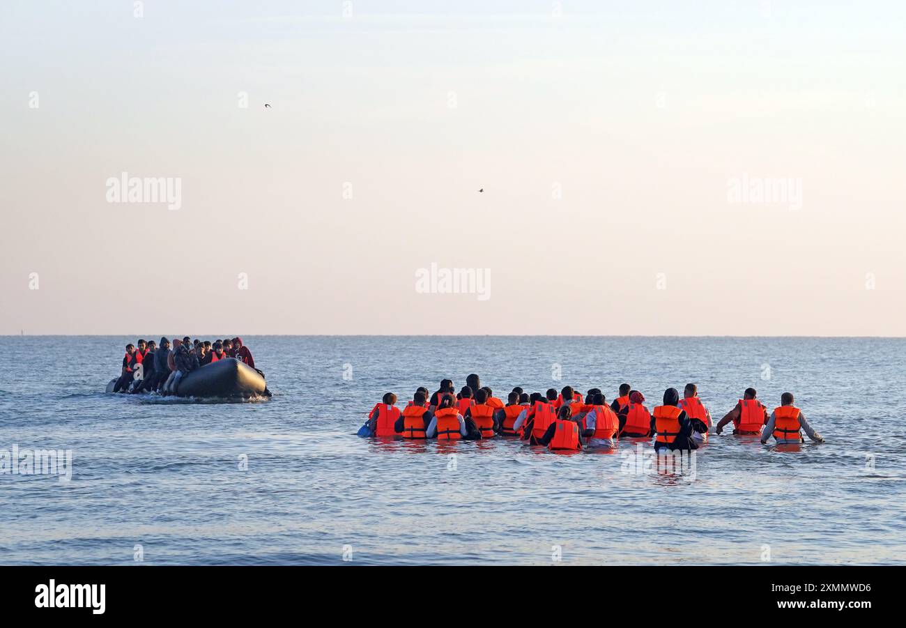 A group of people thought to be migrants wade through the sea to ...