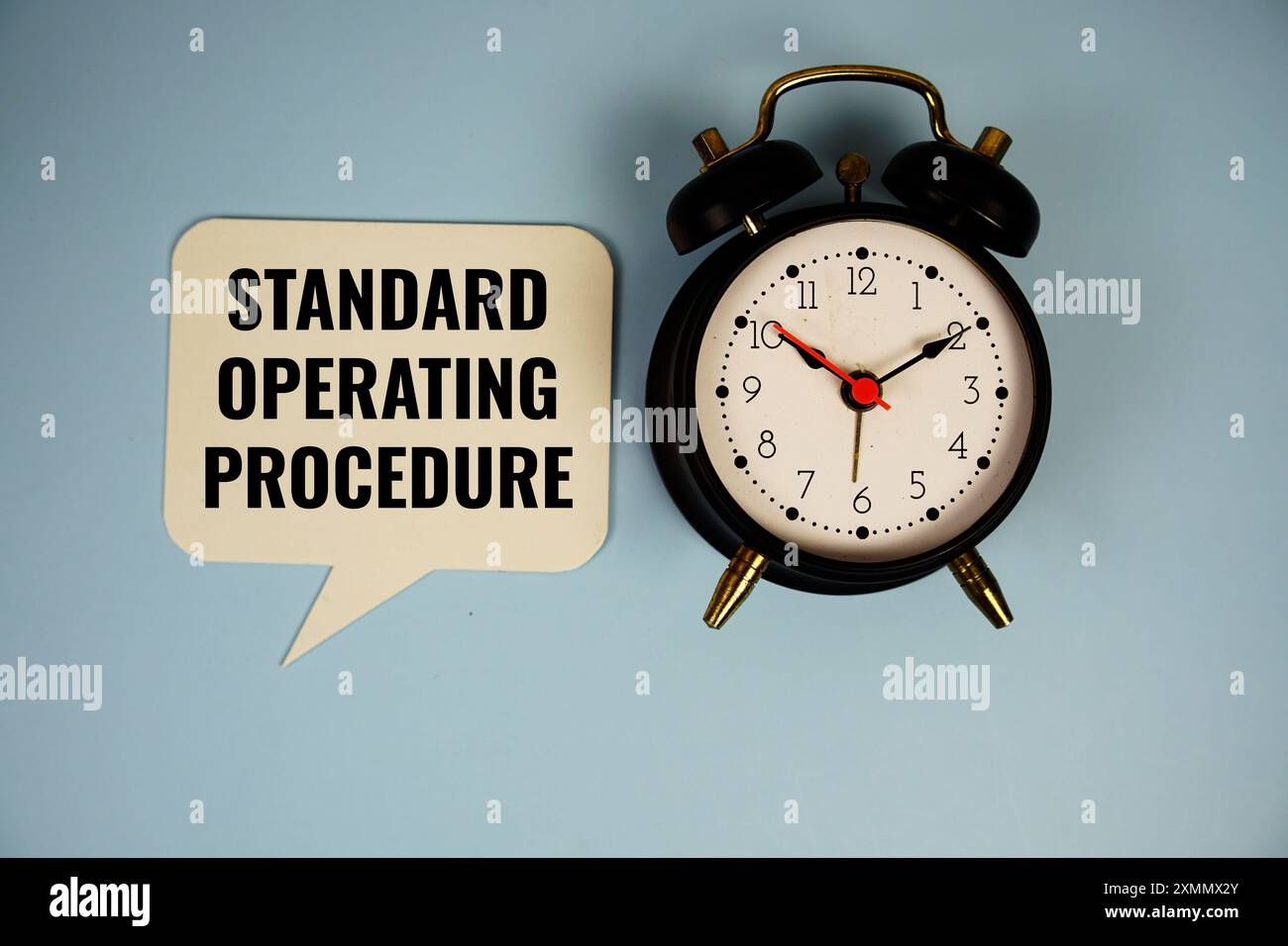 Standard Operating Procedure text on speech bubble with alarm clock top view on blue background ...