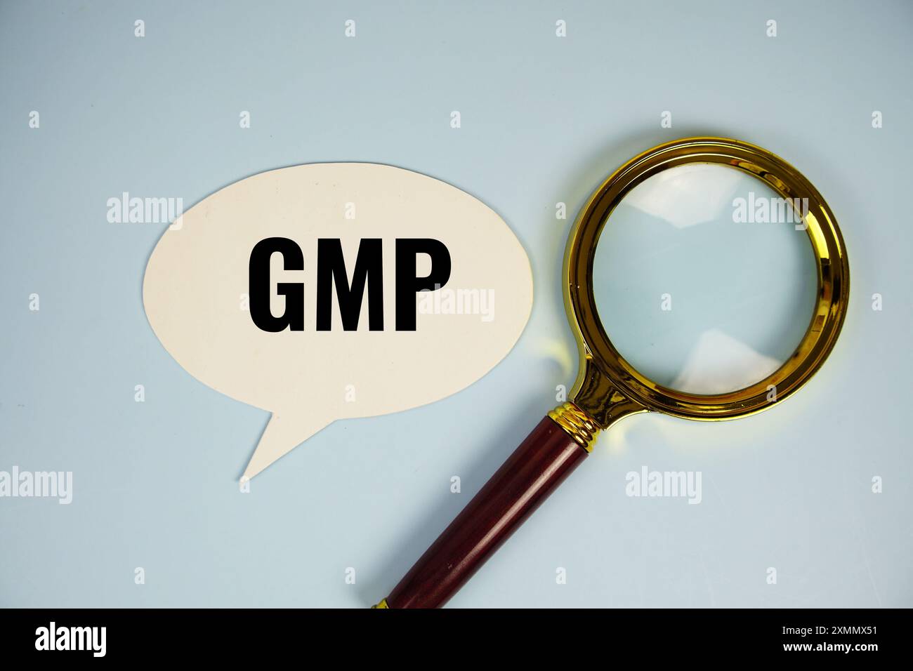 GMP text on speech bluble with magnifying glass top view on blue ...