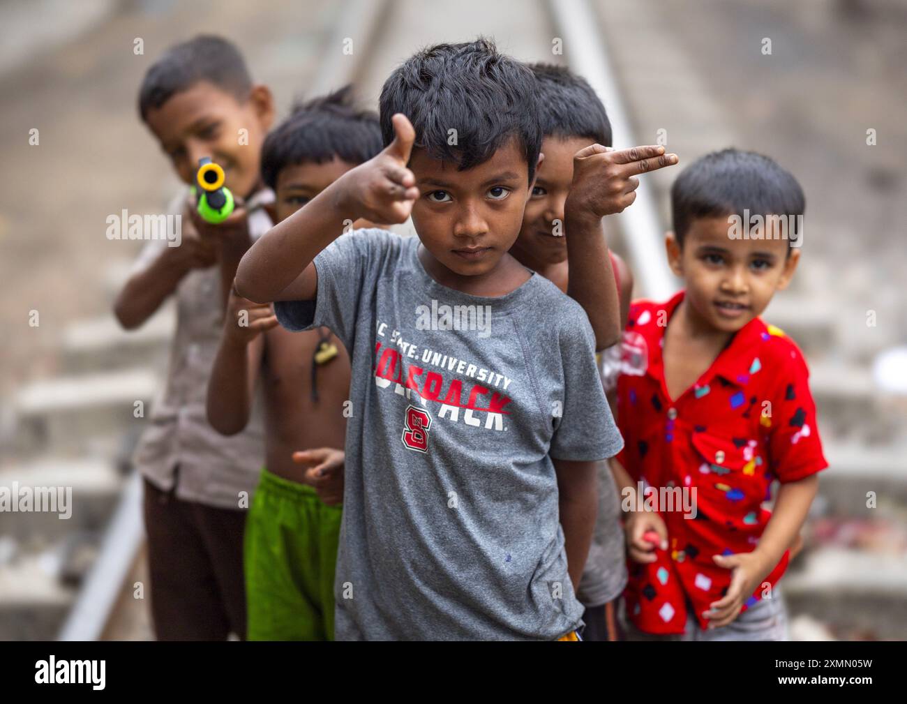Bangladeshi boy miming guns with hands along a railway track ...