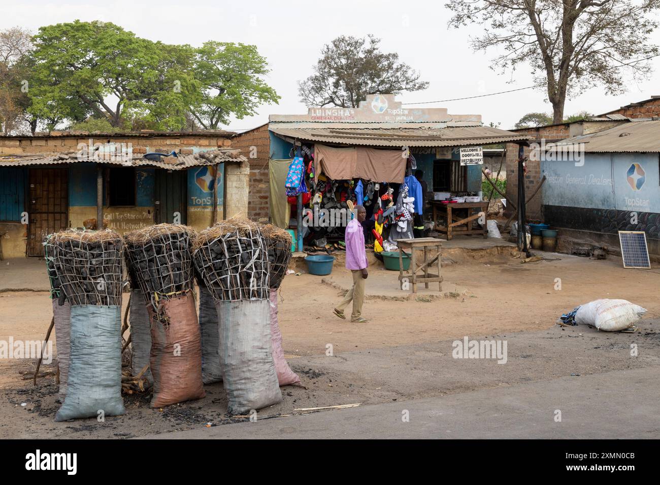 Roadside scene in Kabwe with large bags of charcoal for sale against a ...