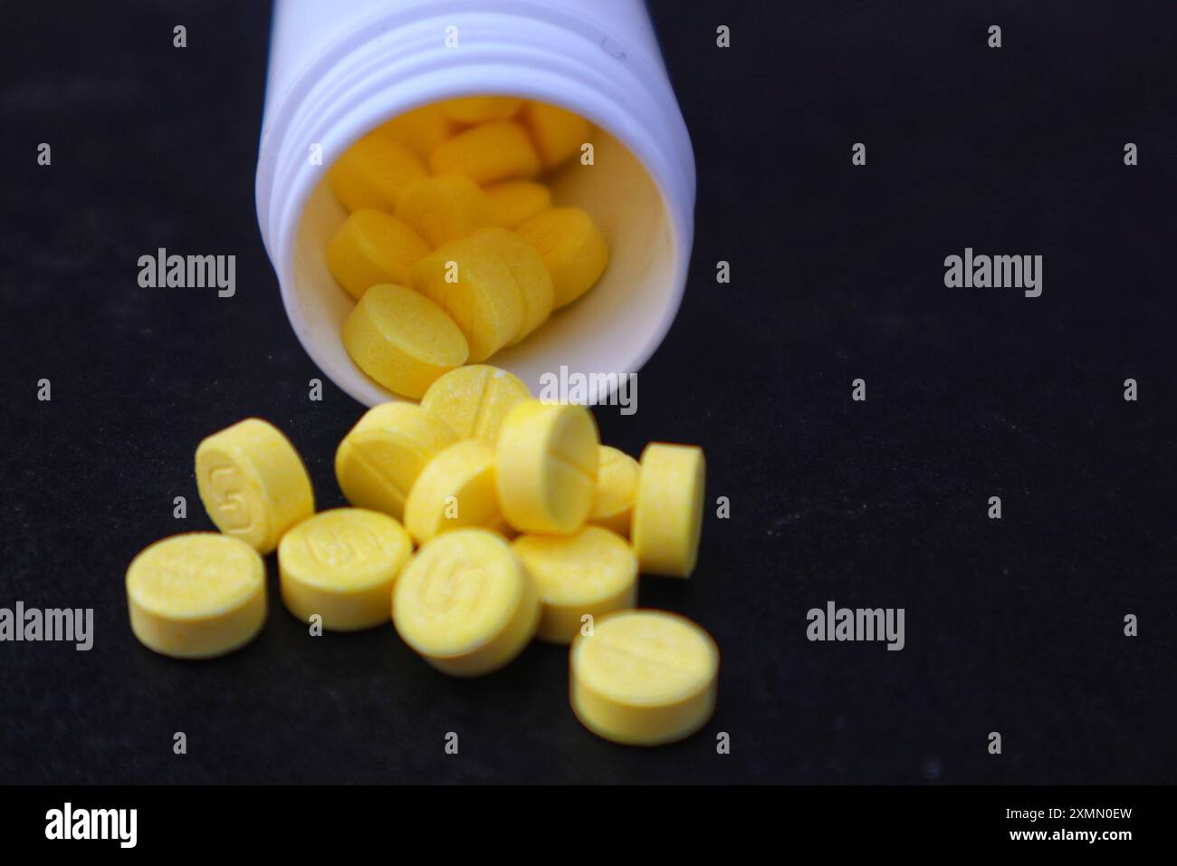 Yellow colored medicine tablets or vitamin C medication spilling from ...