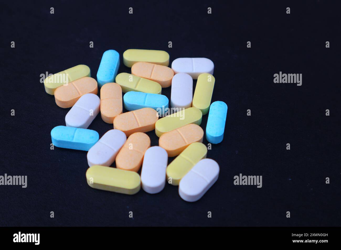 Different types of caplet pills mixed with close up view on black ...