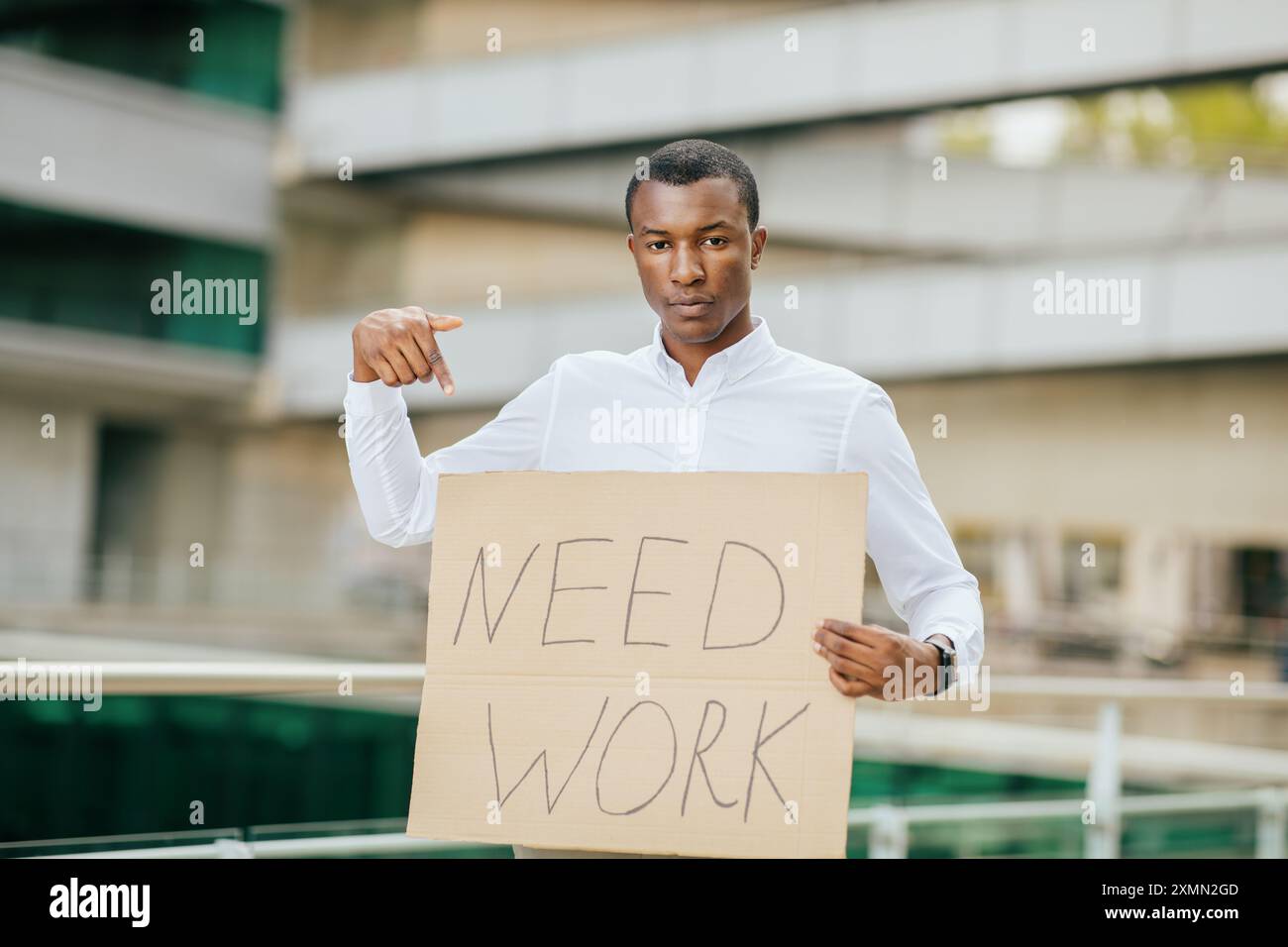 Young Man Holding Need Work Sign in Urban Setting Stock Photo - Alamy